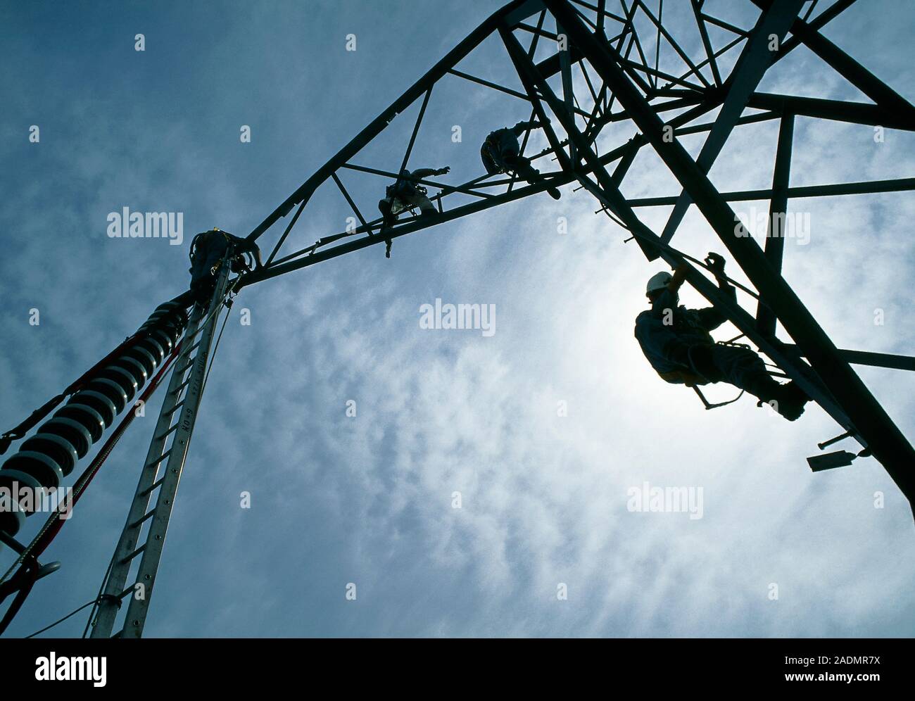 Electricity pylon maintenance. Silhouetted technicians working on the ...