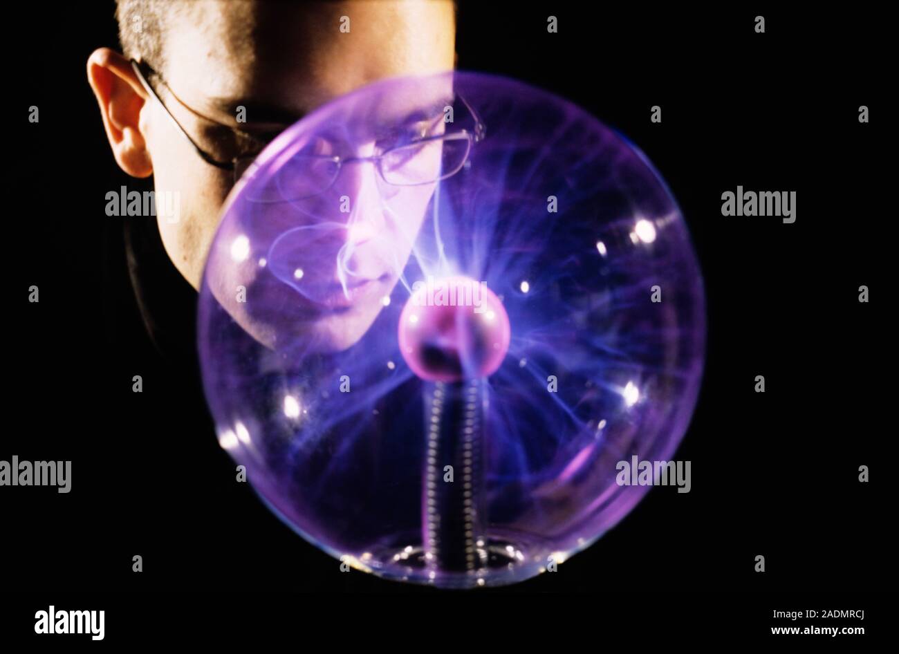 Plasma sphere. Man's nose touching a plasma sphere and attracting ...