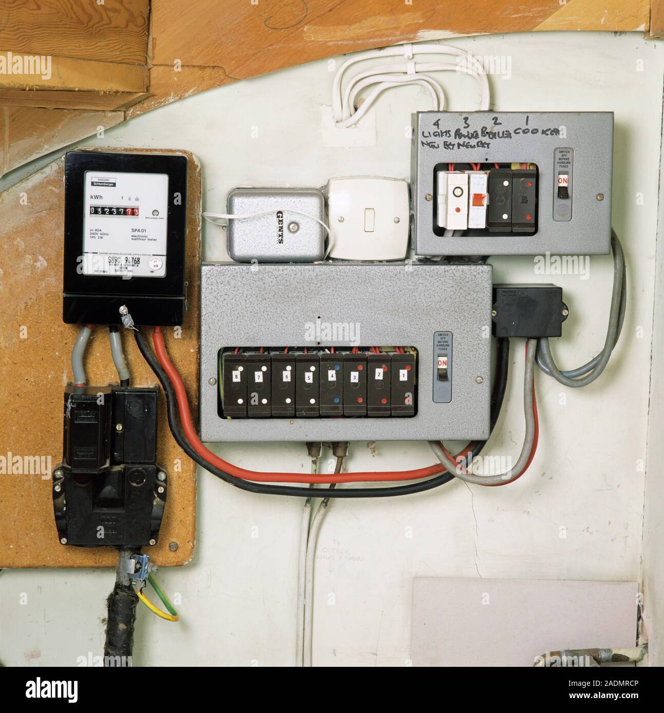 Electricity meter and fuse boxes on a wall in a house. The meter, black ...