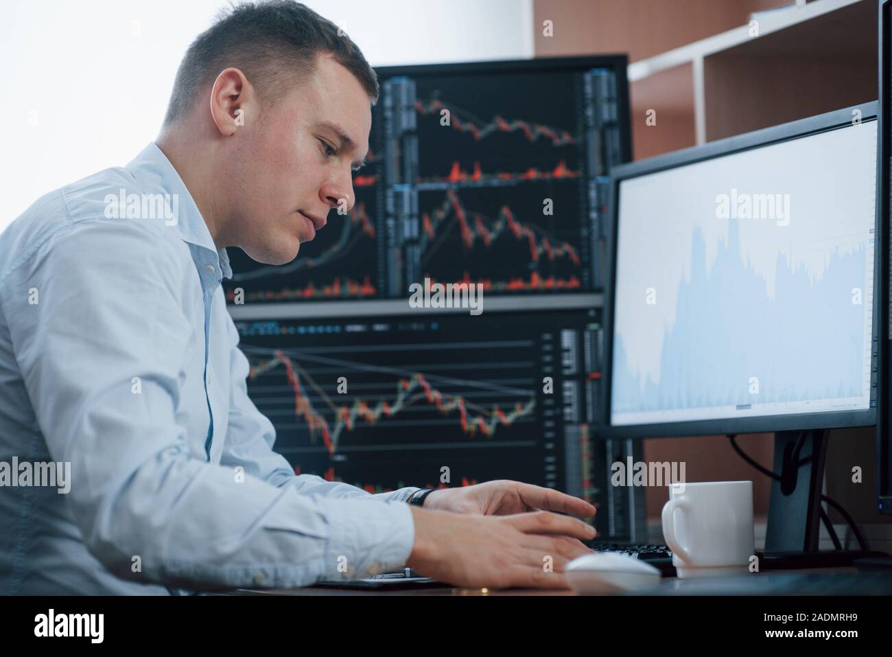 Man working online in the office with multiple computer screens in ...