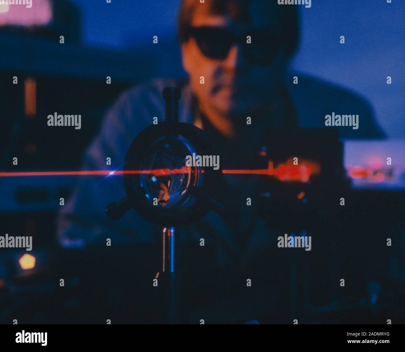 Laser research. A researcher studies a laser beam in a laboratory. The ...