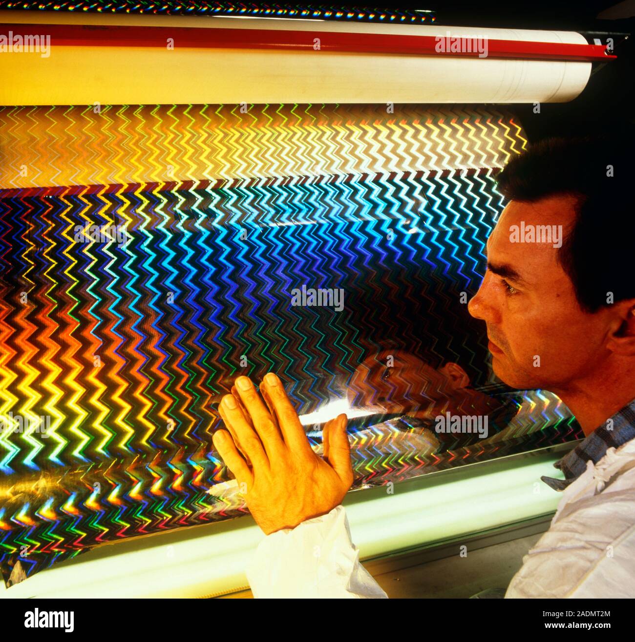 Holographic material. Technician carrying out visual quality control on ...