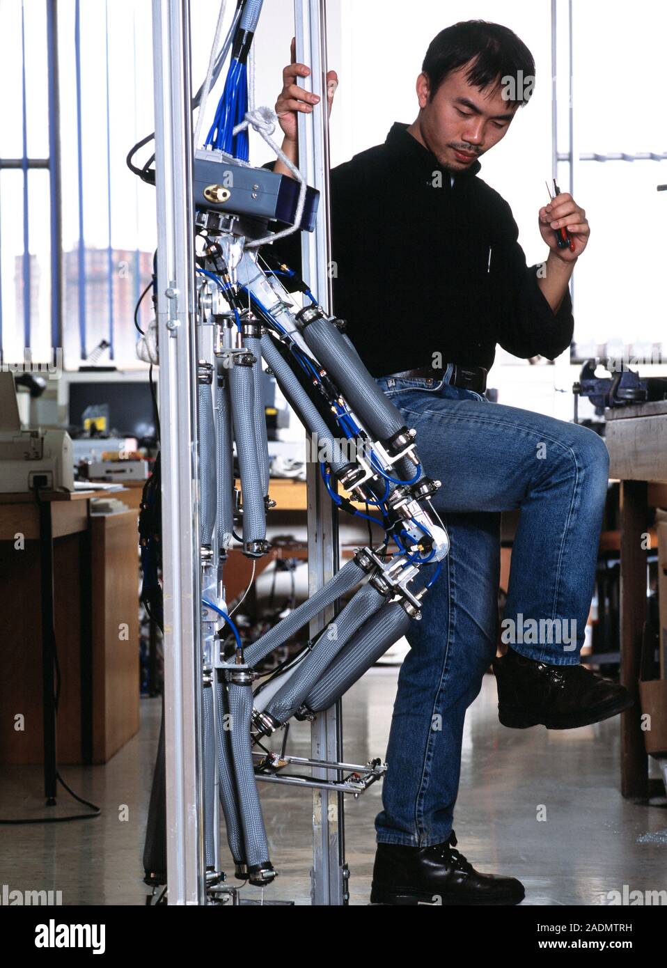 Robotic legs. Researcher mimicking the posture of a pair of robotic ...