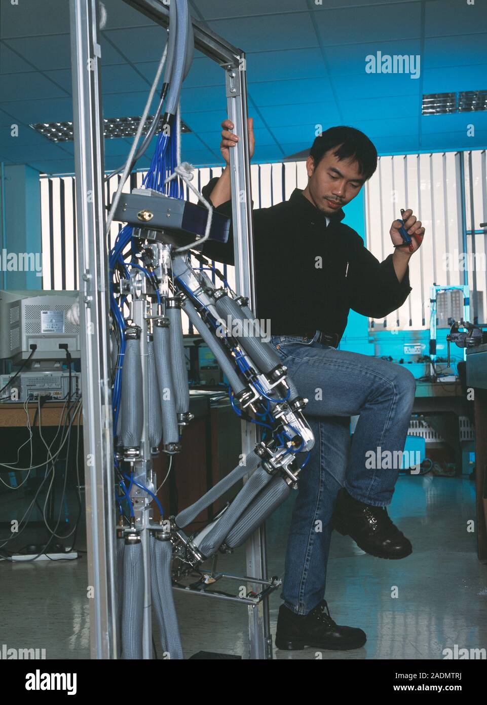 Robotic legs. Researcher mimicking the posture of a pair of robotic ...