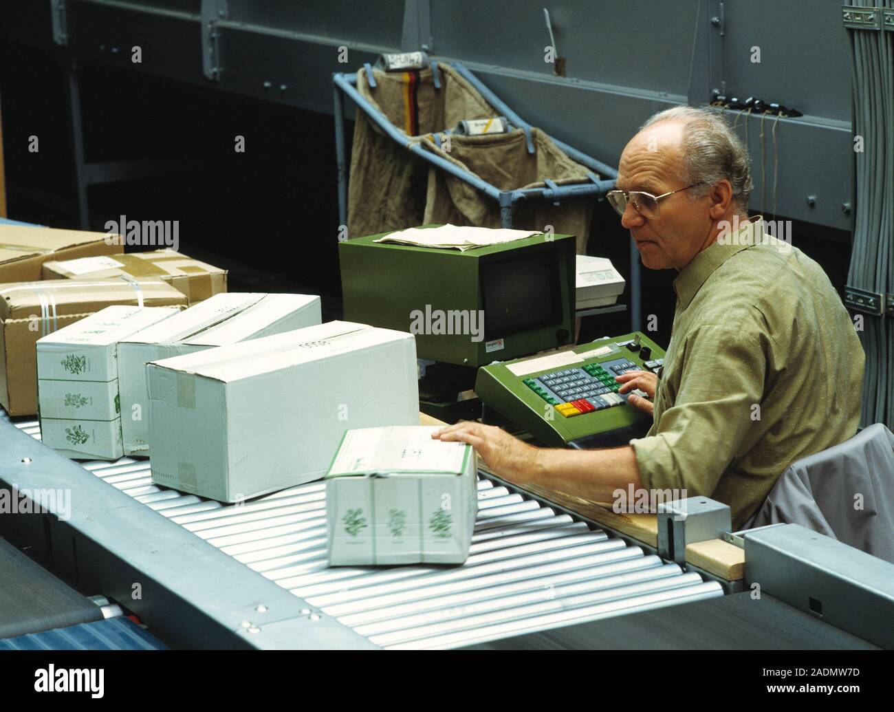 Parcel sorting. Postal worker sorting packages along a conveyor belt ...
