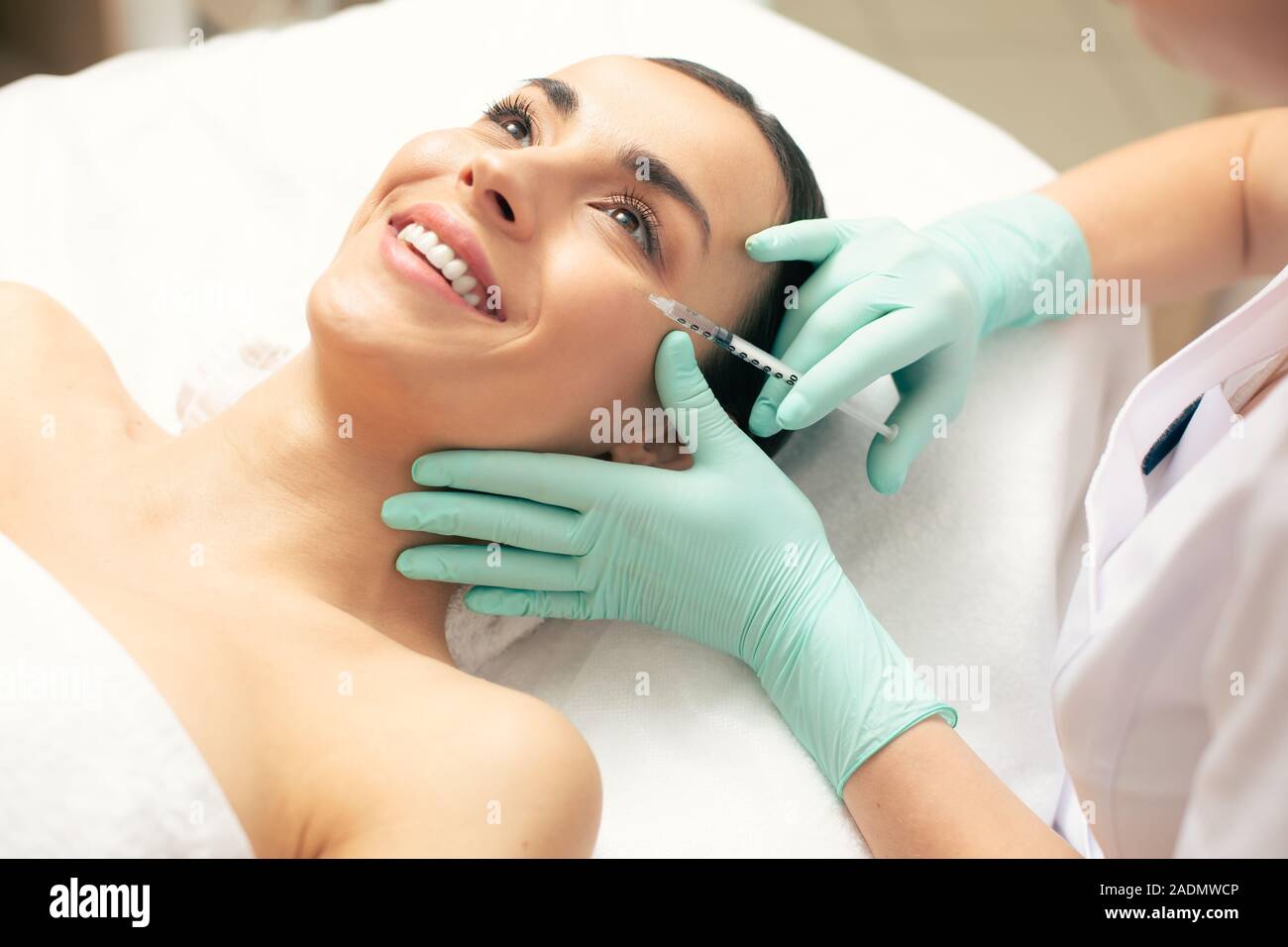 Happy woman smiling and getting necessary face injection Stock Photo ...