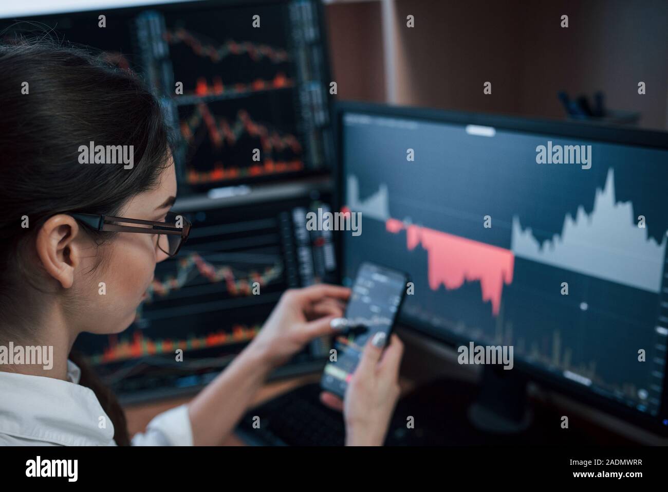 In eyeglasses. Woman working online in the office with multiple ...
