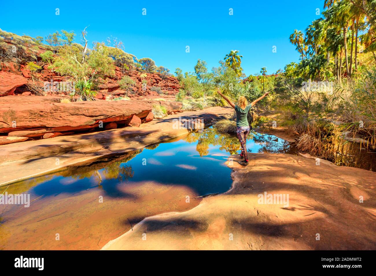 Carefree woman enjoying sandstone cliffs and red Cabbage Palm ...