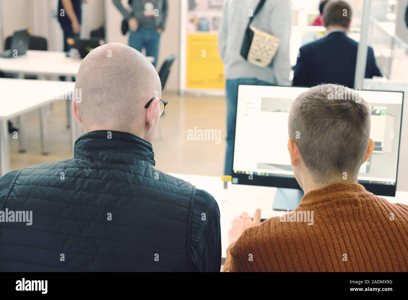 Back view of two male managers or workers look at laptop mock up screen ...