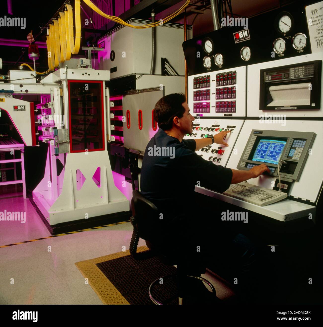 Circuit board manufacture. Technician operating a computerised control ...