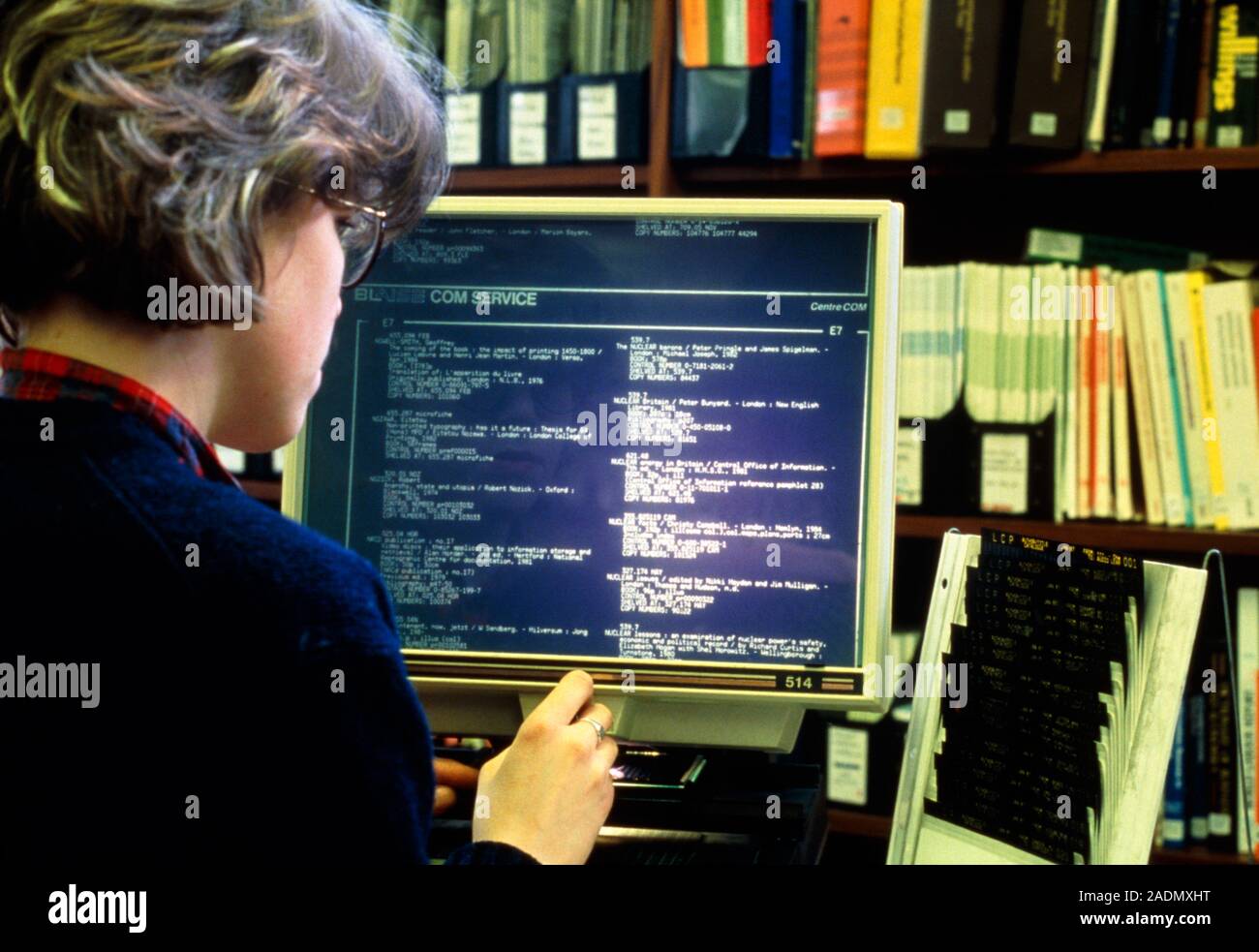 Young woman using the micofiche index at a London lending library ...