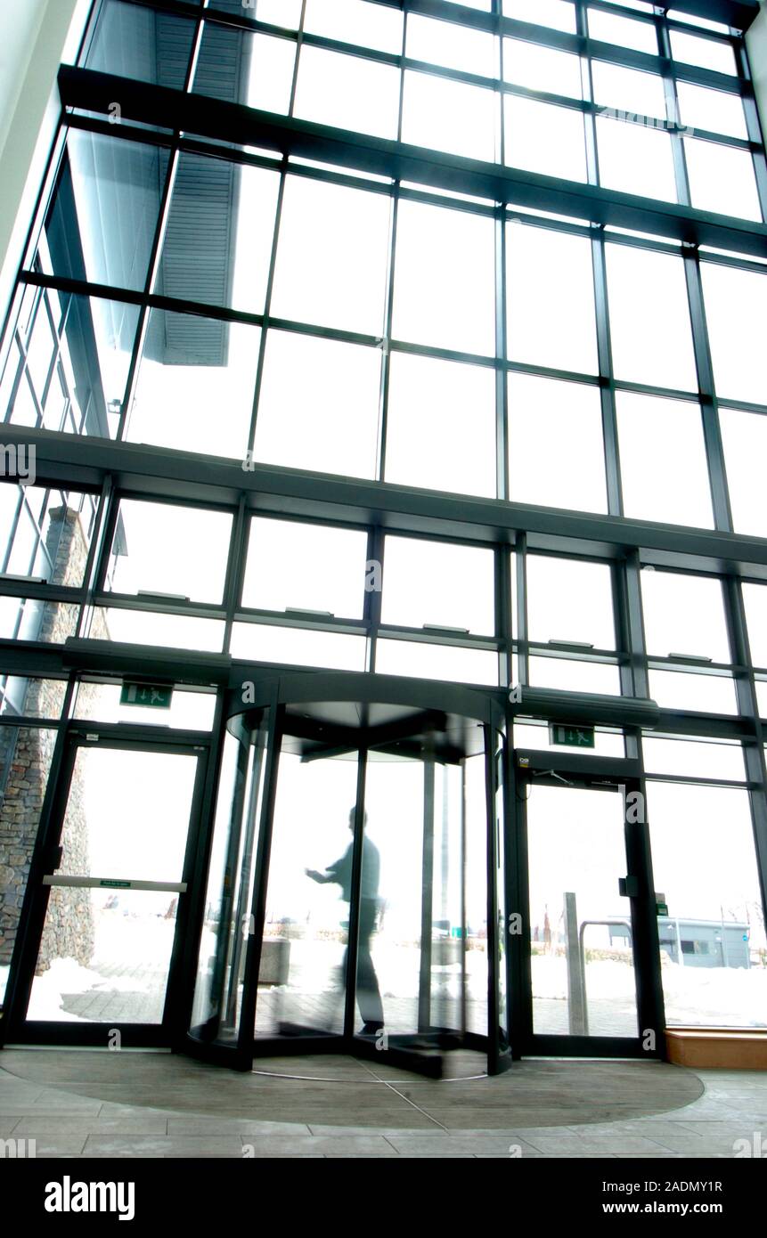 MODEL RELEASED. Man leaving office building through a revolving door ...