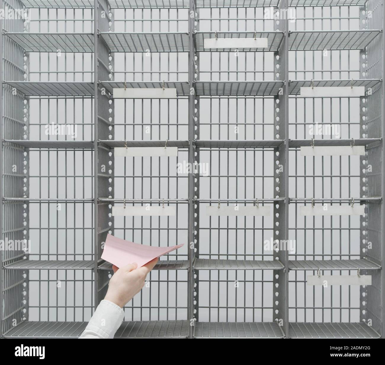 MODEL RELEASED. Office pigeon holes. Office worker filing some ...