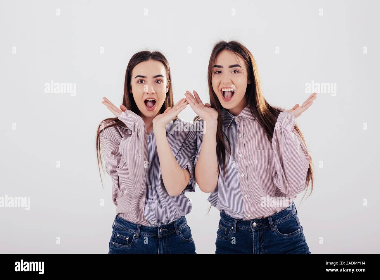 Expression of wonder. Two sisters twins standing and posing in the ...