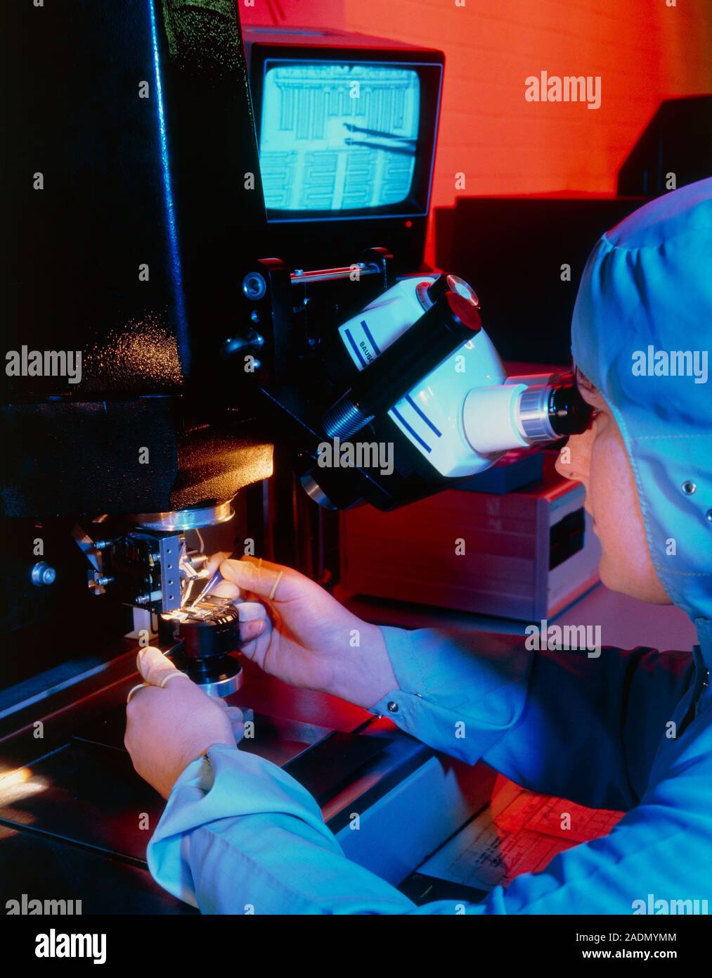 Technician using a light microscope in the autobonding stage of ...