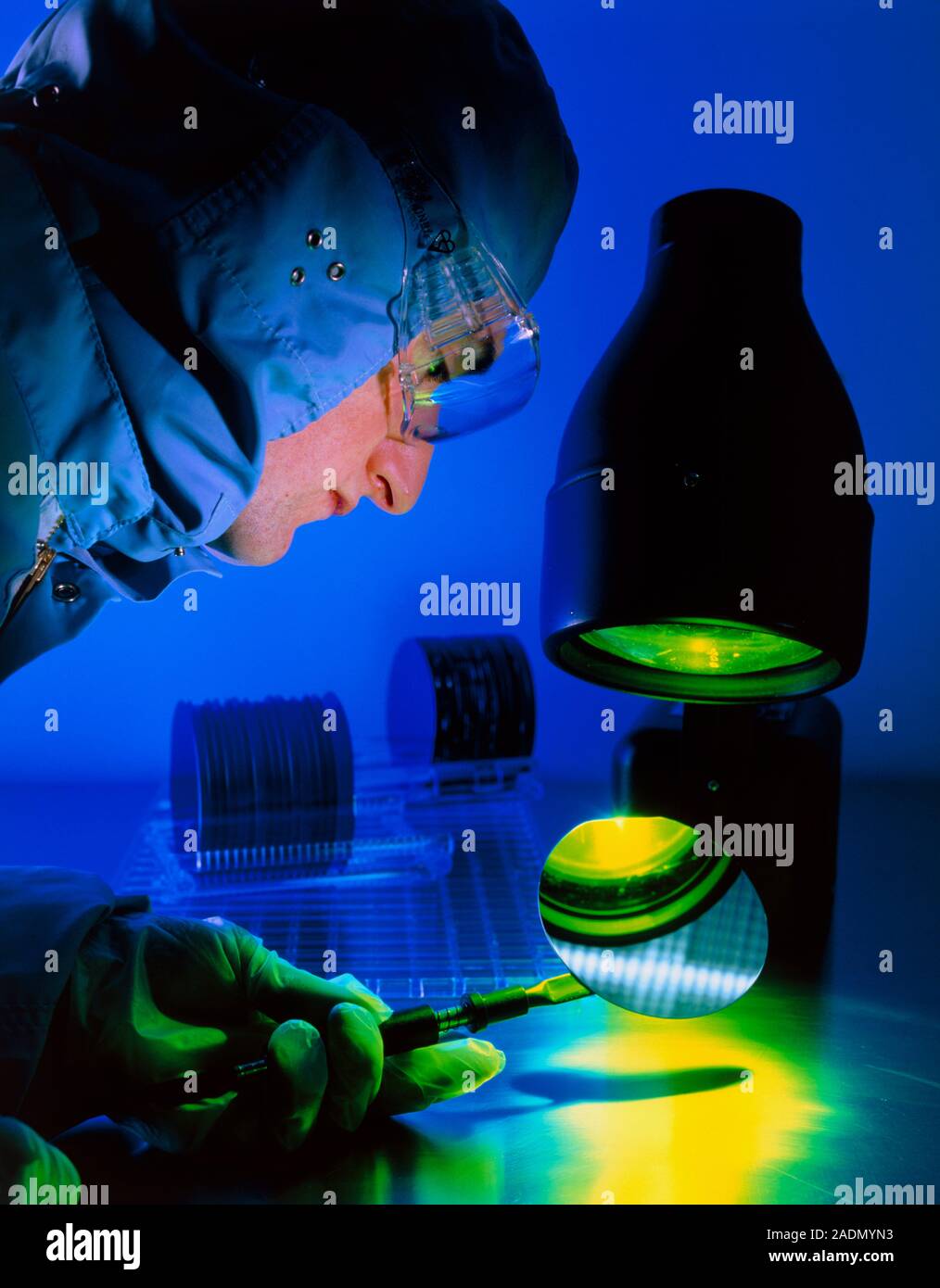 Technician wearing clean room clothing making visual inspection of ...