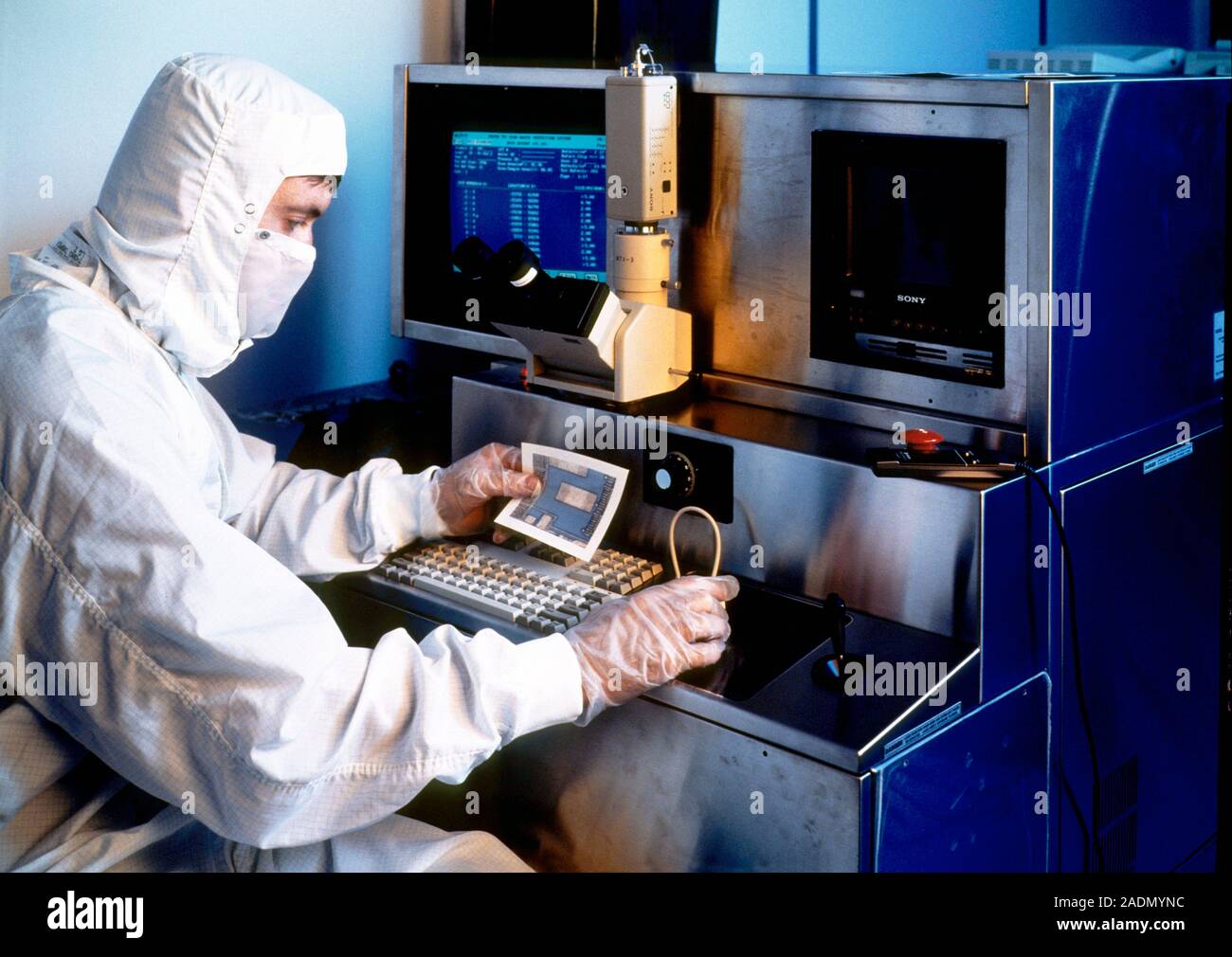 Silicon wafer inspection. A technician holds a photograph of part of a ...