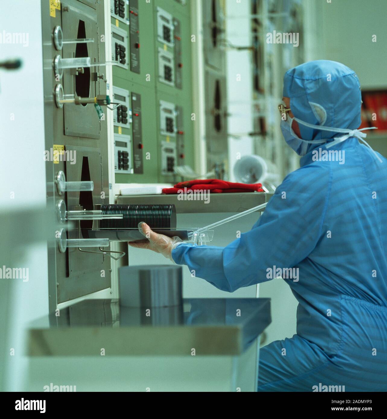Microchip manufacture. Technician in a clean room prepares ...