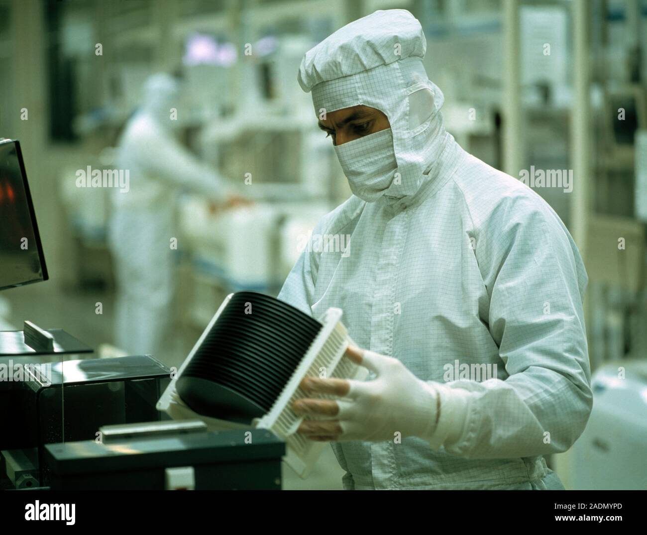 Semiconductor manufacture. Technician in a clean room facility ...