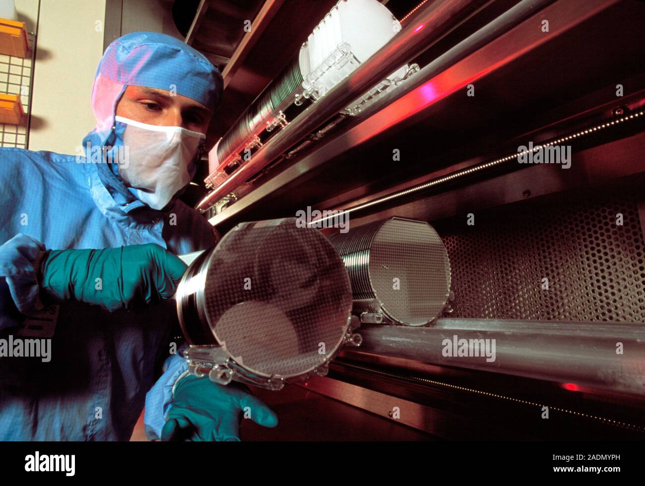 Microchip manufacture. Technician putting a silicon wafer into an oven ...