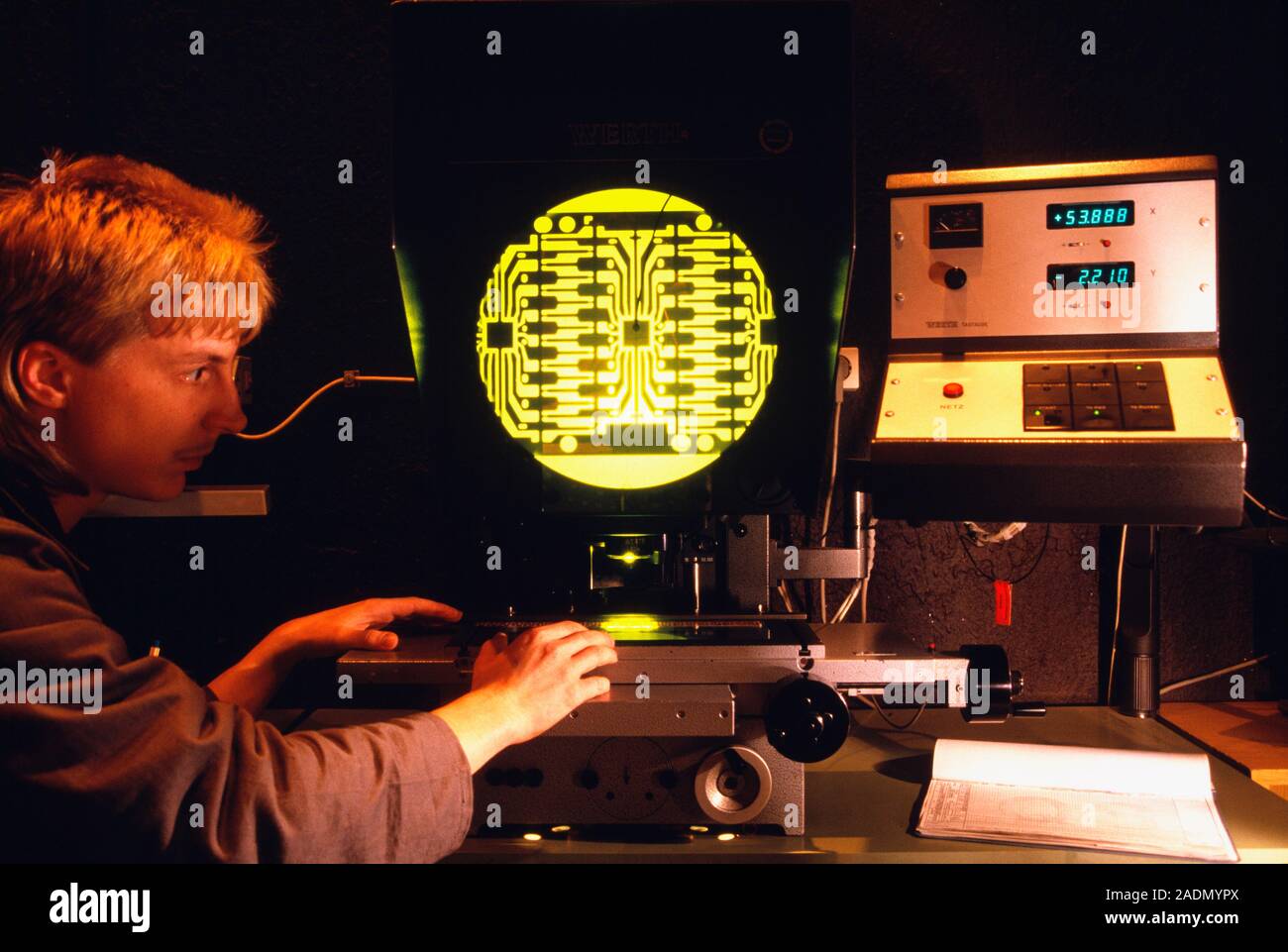 Semiconductor testing. Technician using a microscope to inspect a ...