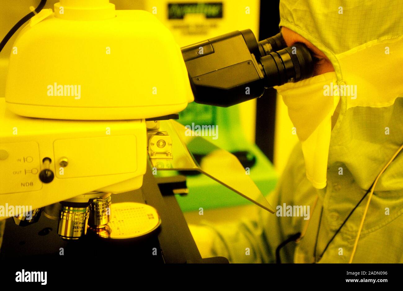 MEMS production. Clean room technician using a microscope to examine a ...