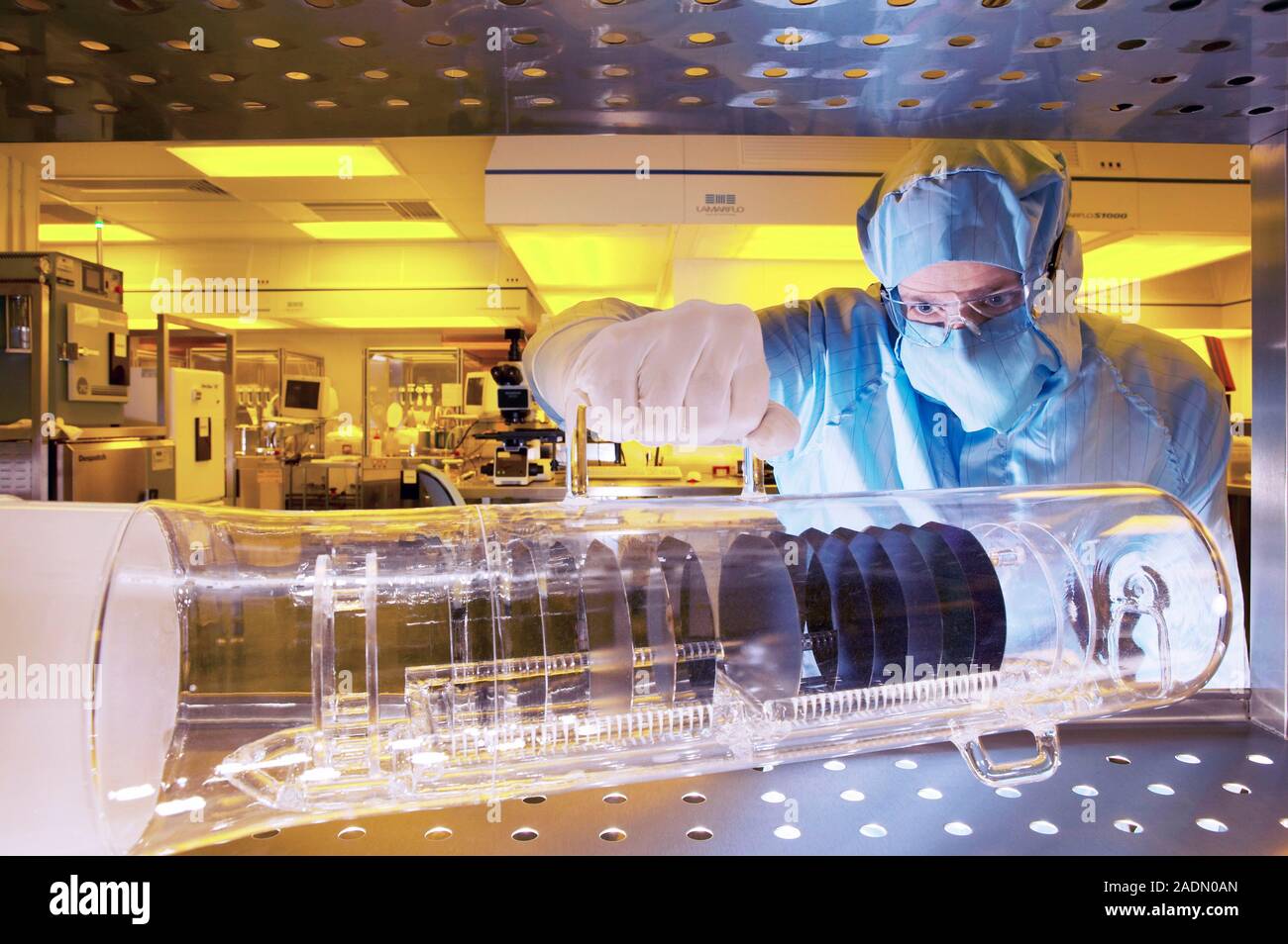 MODEL RELEASED. MEMS production. Clean room technician lifting a ...