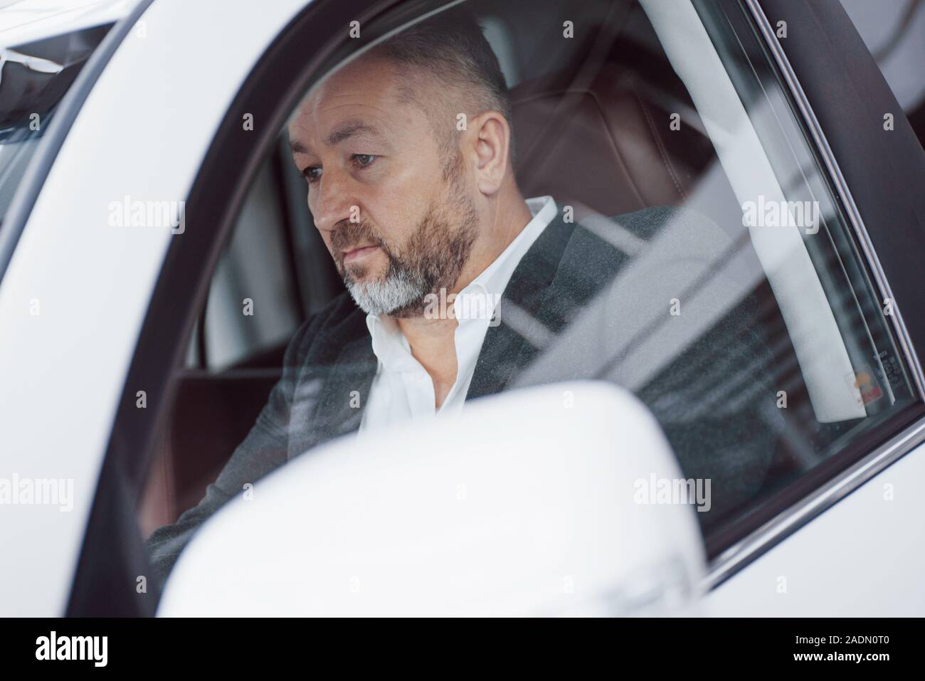 Photo of driver in vehicle. Serious senior businessman testing new car ...
