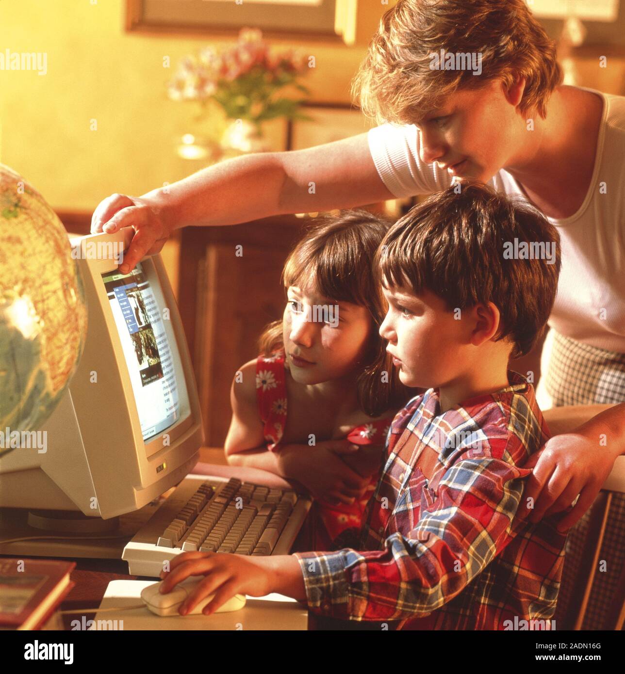Children with computer. Mother helping her children to use a personal ...