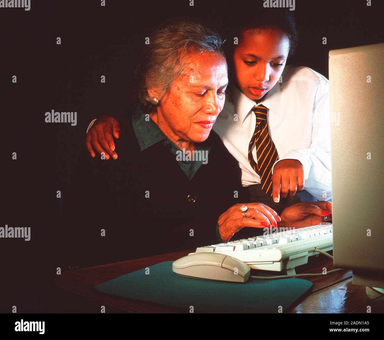 Home computer use. Schoolgirl and her grandmother using a personal ...