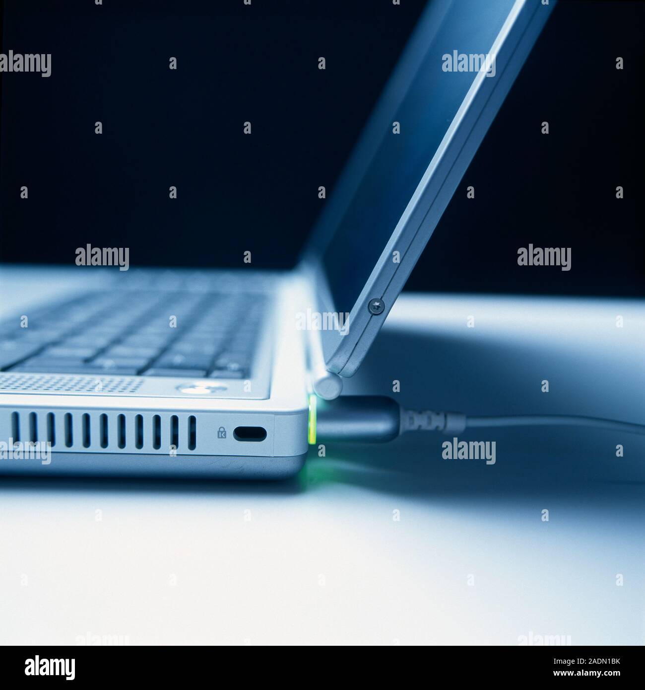 Laptop computer. Side view of the keyboard (left) and screen (right) of ...