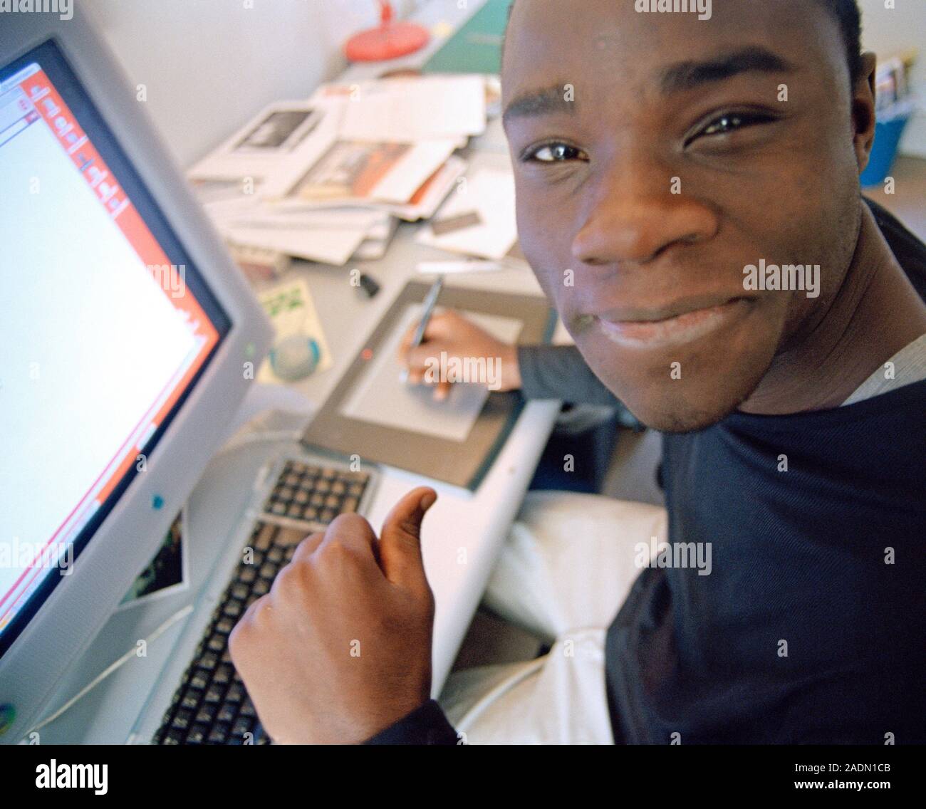 Home computing. Teenage boy sitting at his personal computer. He is ...