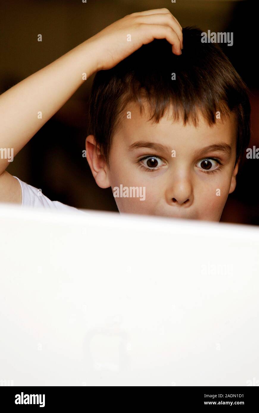 MODEL RELEASED. Laptop computer use. Young boy scratching his head ...