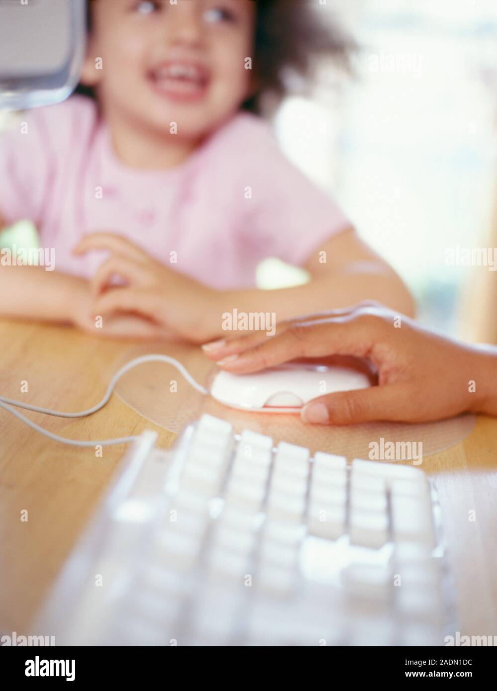MODEL RELEASED. Computer use. Three year old girl watching her mother ...
