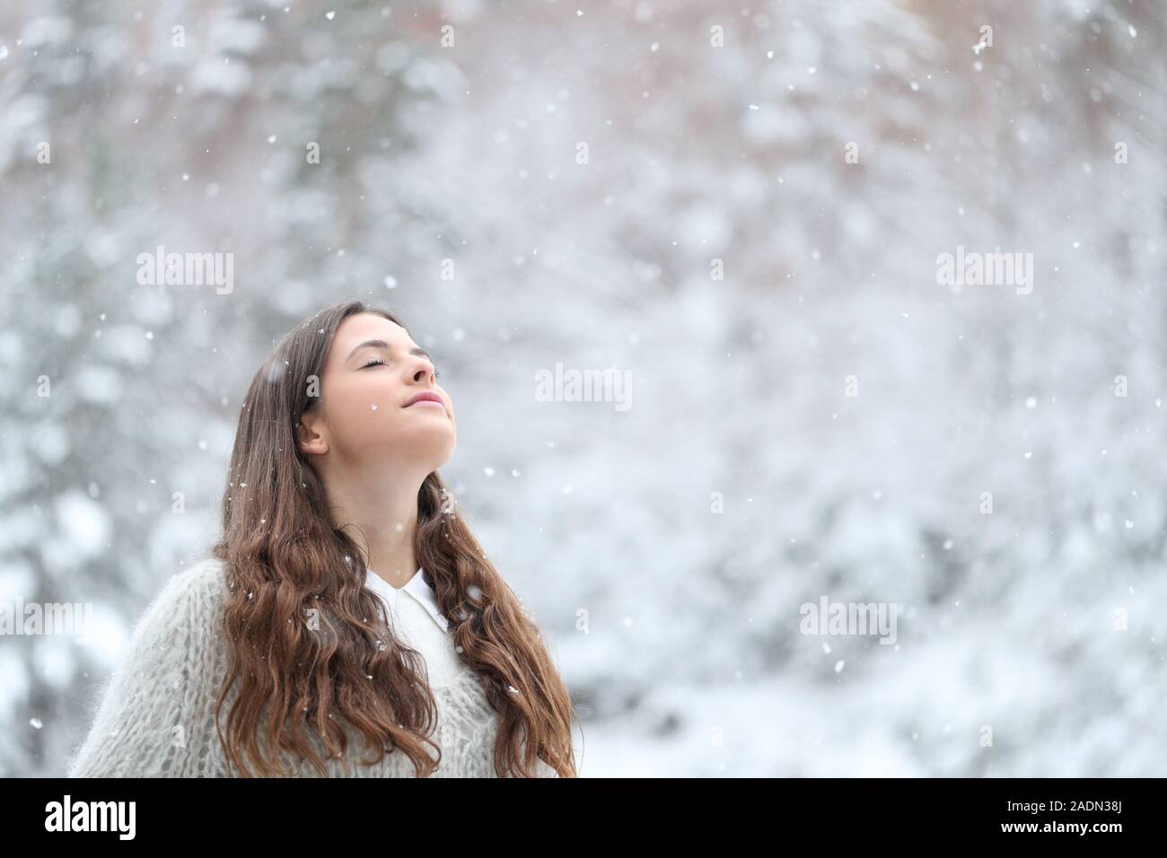 Relaxed girl breathing fresh air enjoying snow in winter in the ...