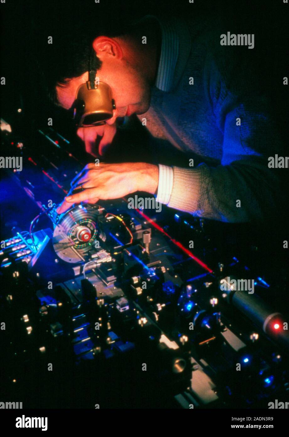 Compact disc manufacture. A researcher checks the position of a compact ...