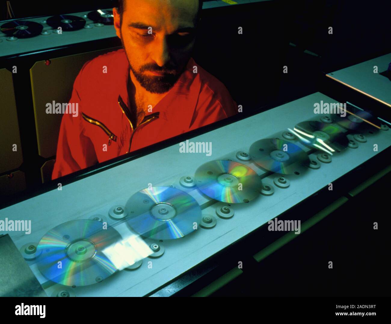 Compact disc manufacture. Time- exposure image of a technician visually ...