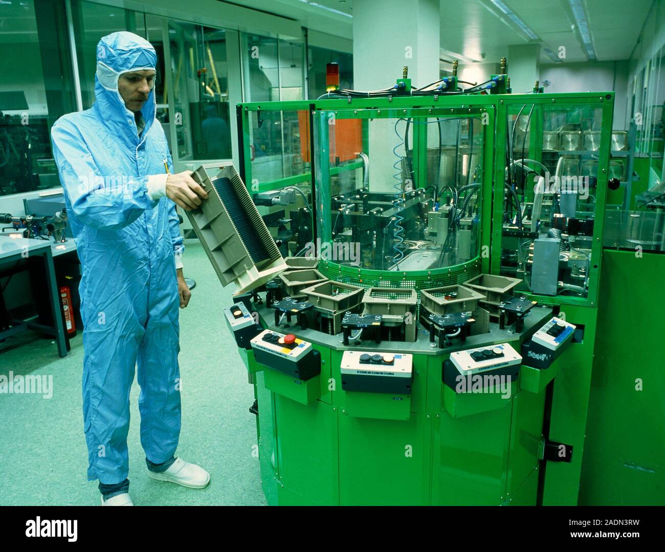 Compact disc manufacture. Worker operates plastic moulding equipment ...