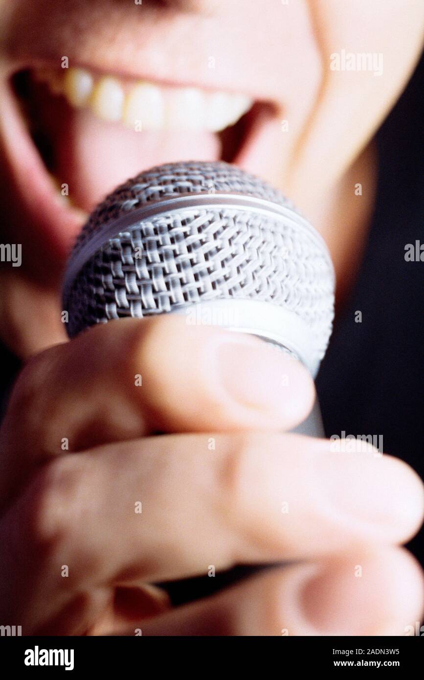 Microphone use. Man speaking or singing into a hand-held microphone ...