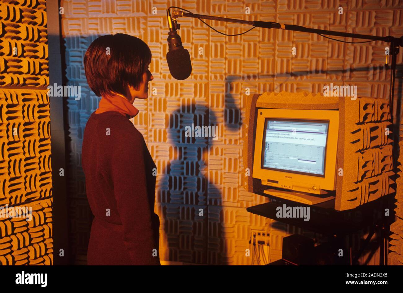 Recording booth. Woman reading text from a screen in a sound recording ...