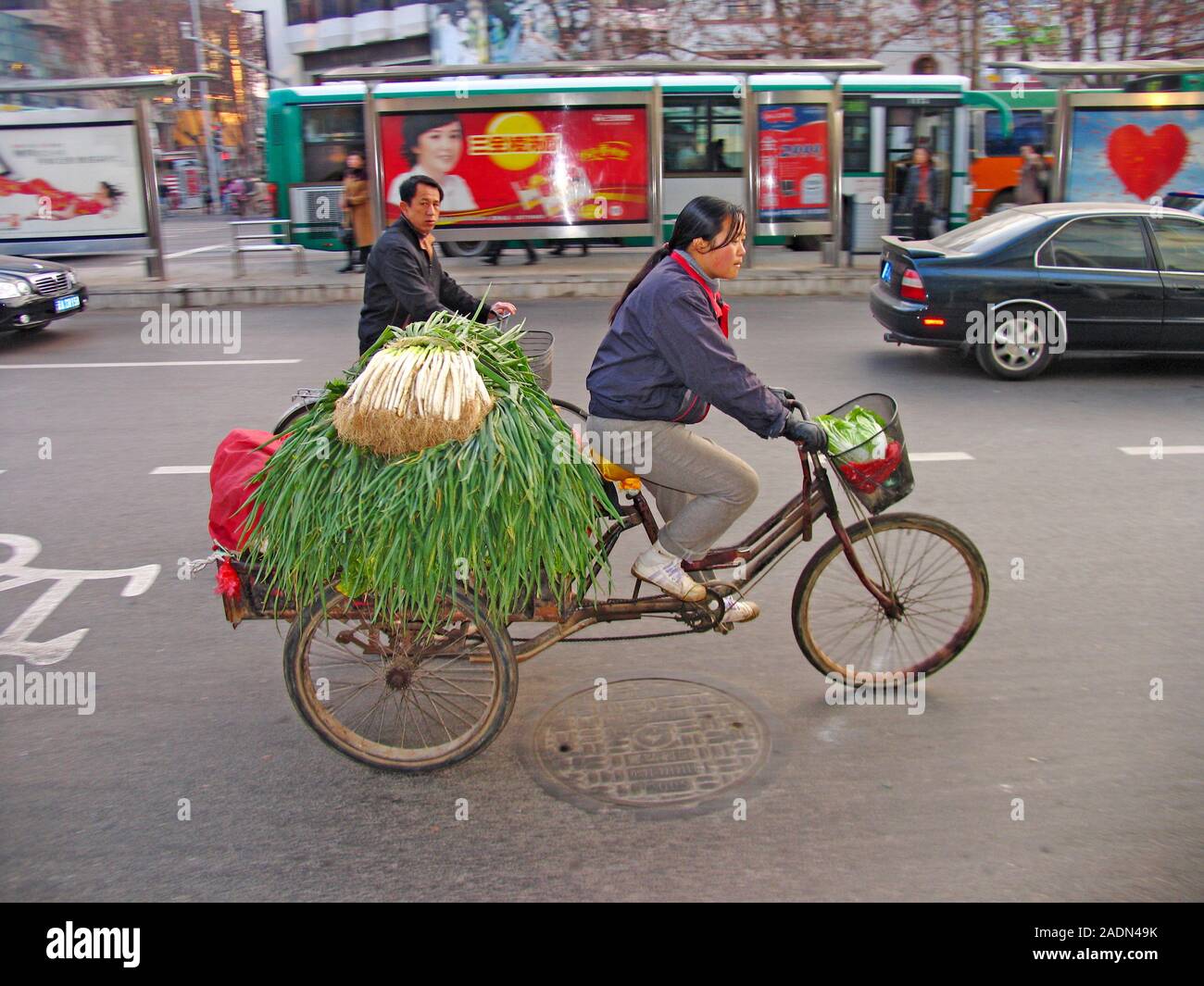 Three-wheeled cycle. Woman transporting vegetables on the back of a ...