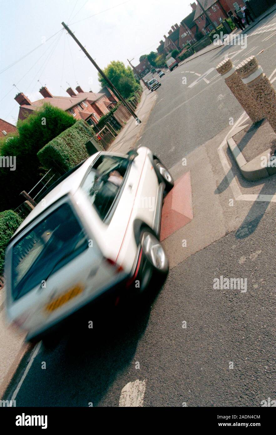 Traffic calming. Car going over a speed bump, used to keep traffic from ...
