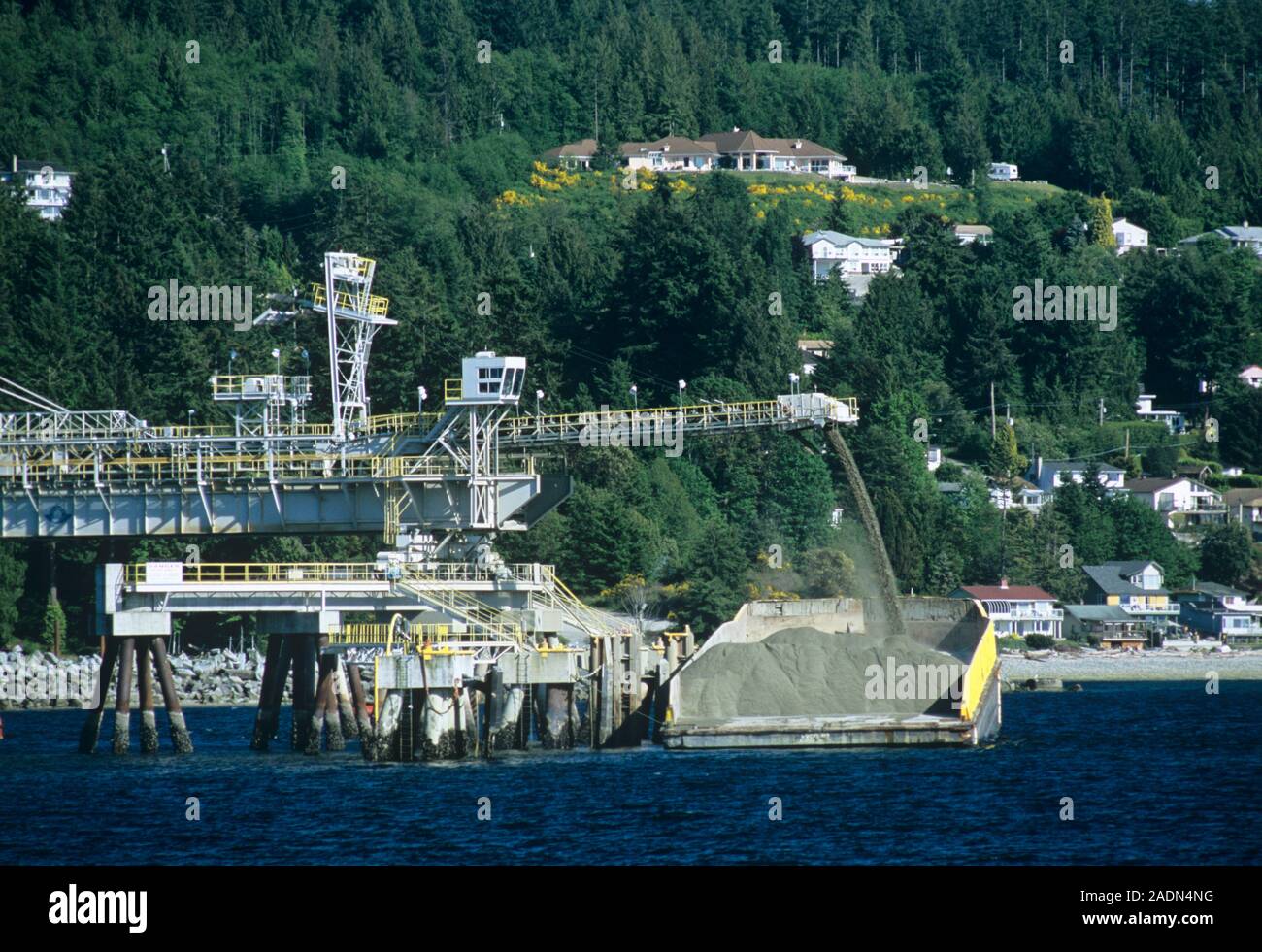 Industrial river barge being loaded with gravel from a conveyor belt ...