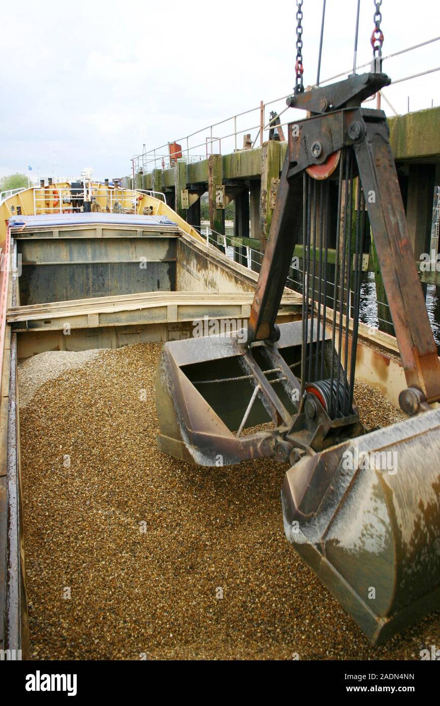 Unloading cargo. Crane unloading aggregate from a motor barge ...