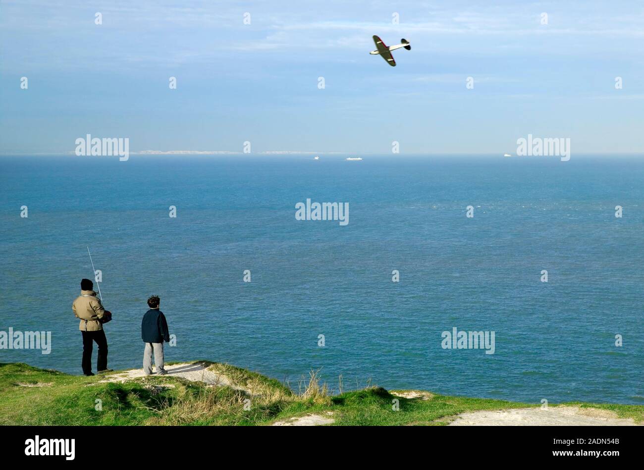 Radio-controlled aircraft. Father and son standing on a cliff over the ...