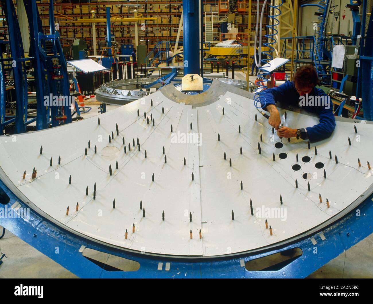 POSED BY MODEL. Aircraft construction. Technician riveting part of the ...