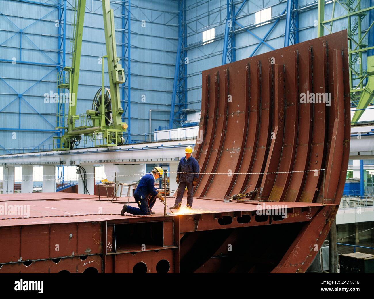 Shipbuilding. Workers welding the prefabricated segments of a ship's ...