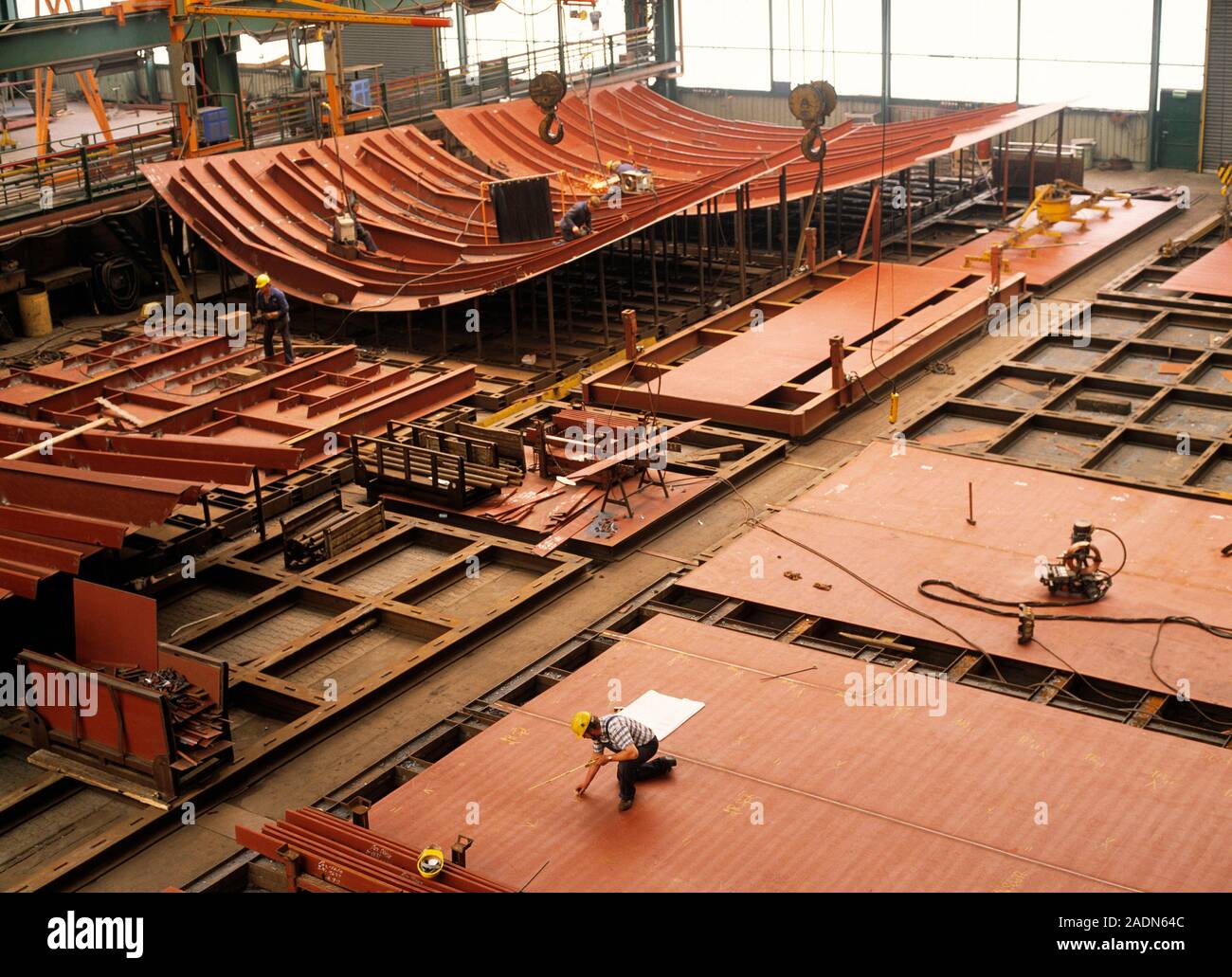 Shipbuilding. Workers welding the prefabricated segments of a ship's ...