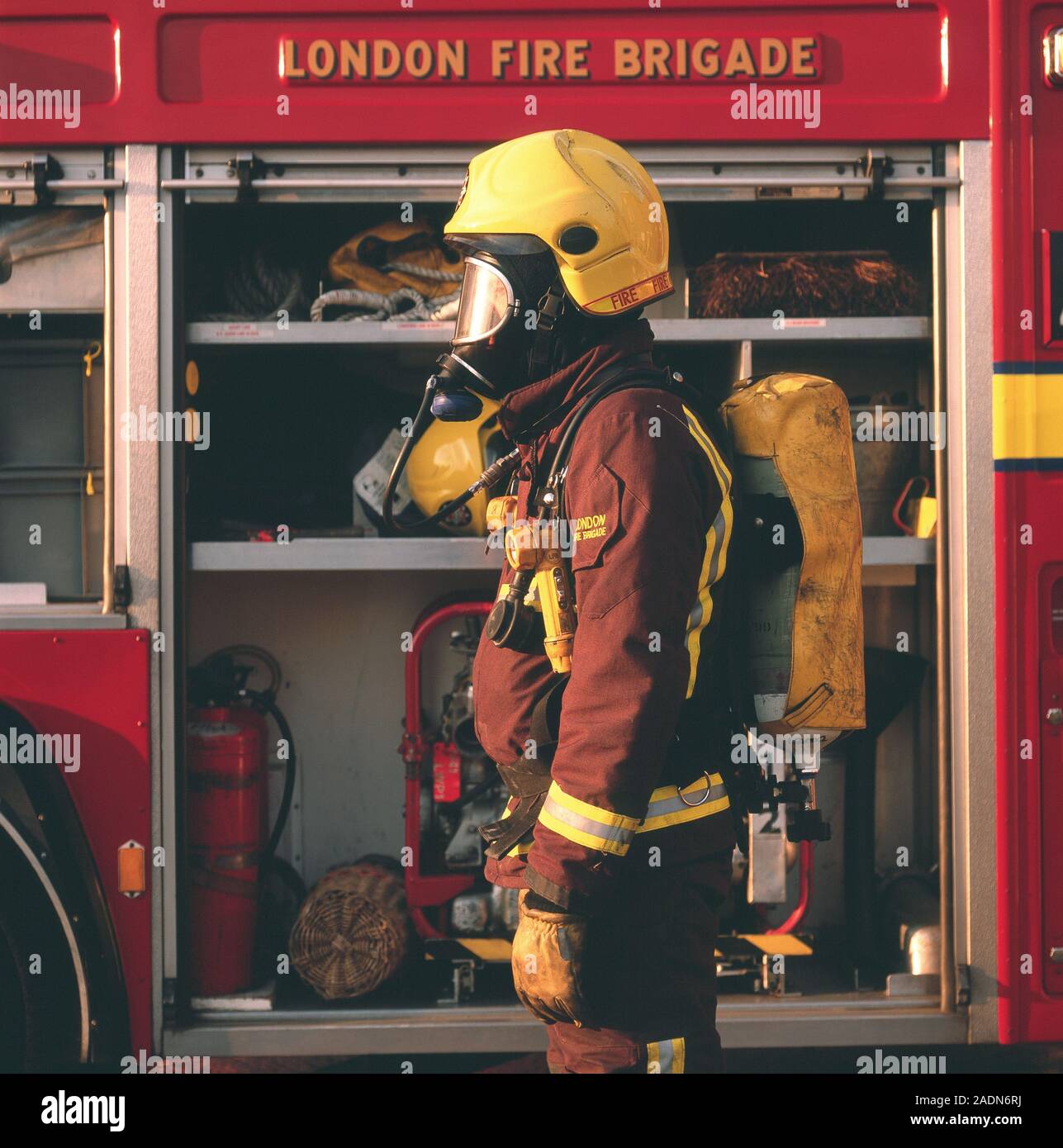 Firefighter standing by a storage cabinet of a fire engine. He is ...