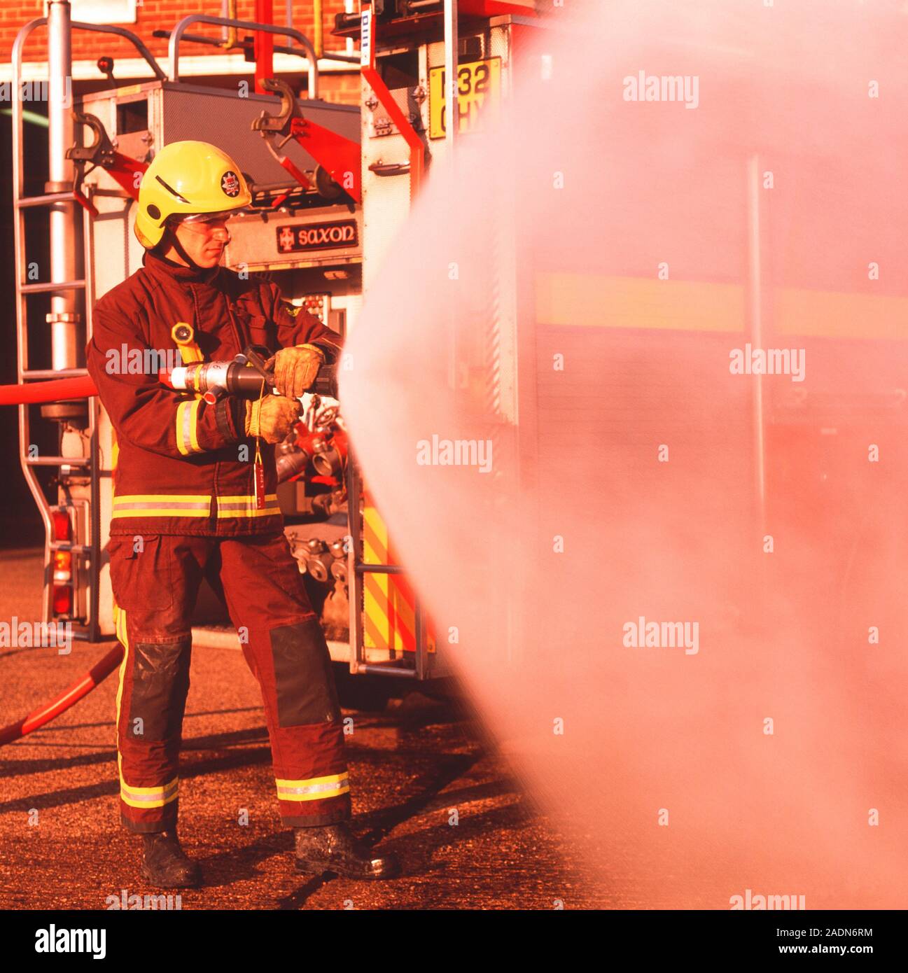 Firefighter using a high-pressure hose to spray water. The hose is ...